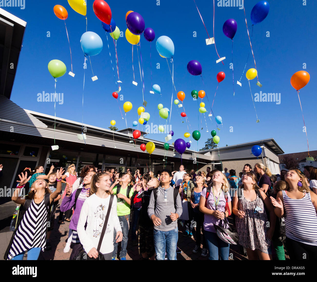 Young students let balloons with their wishes attached rise to the blue ...