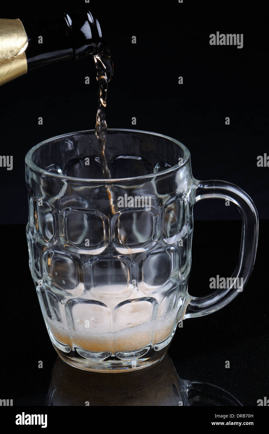 Pouring alcohol from a bottle to a dimpled pint glass Stock Photo - Alamy