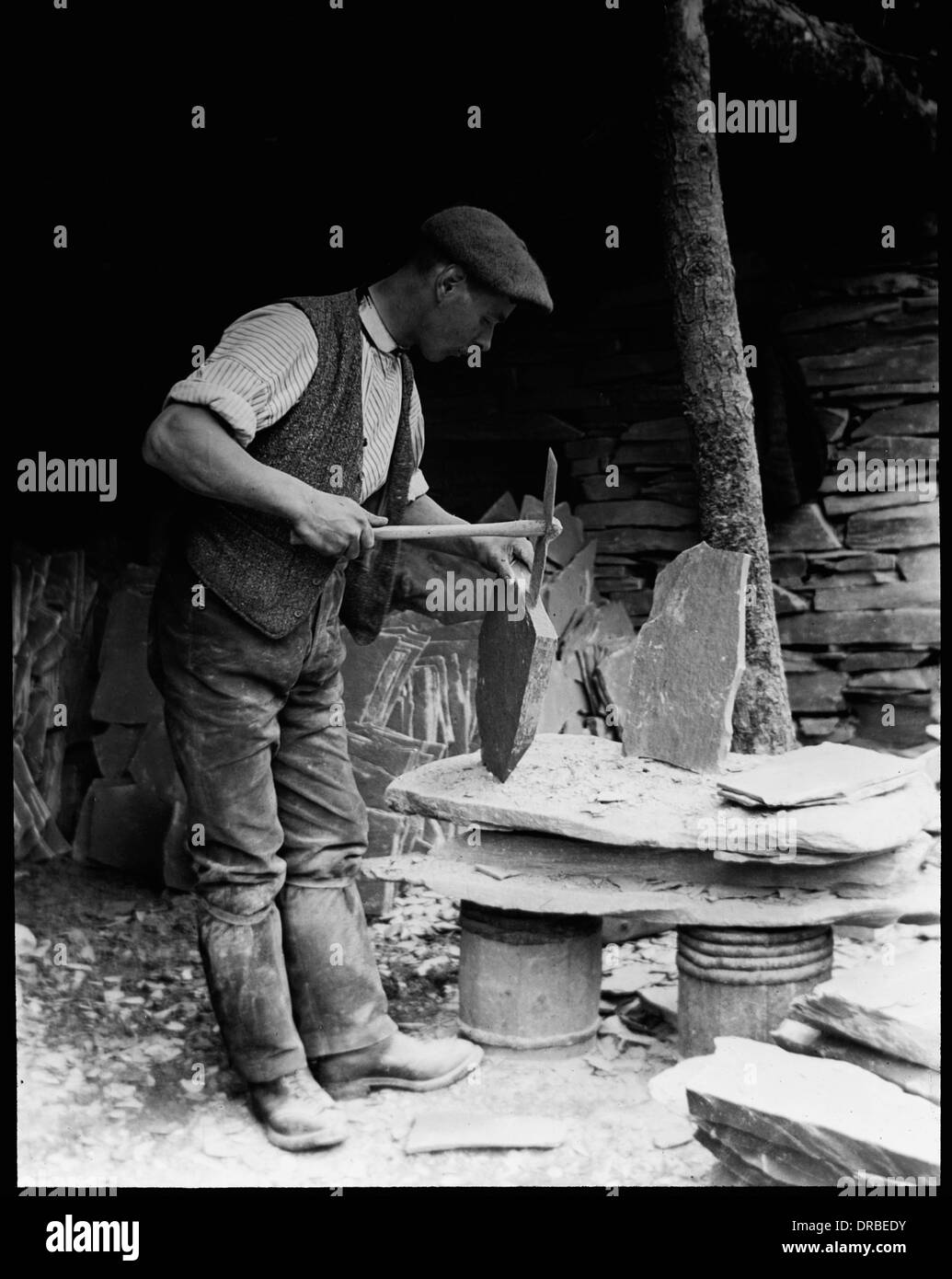 Workman splitting slate (riving) for roofing slates. Langdale, Lake ...