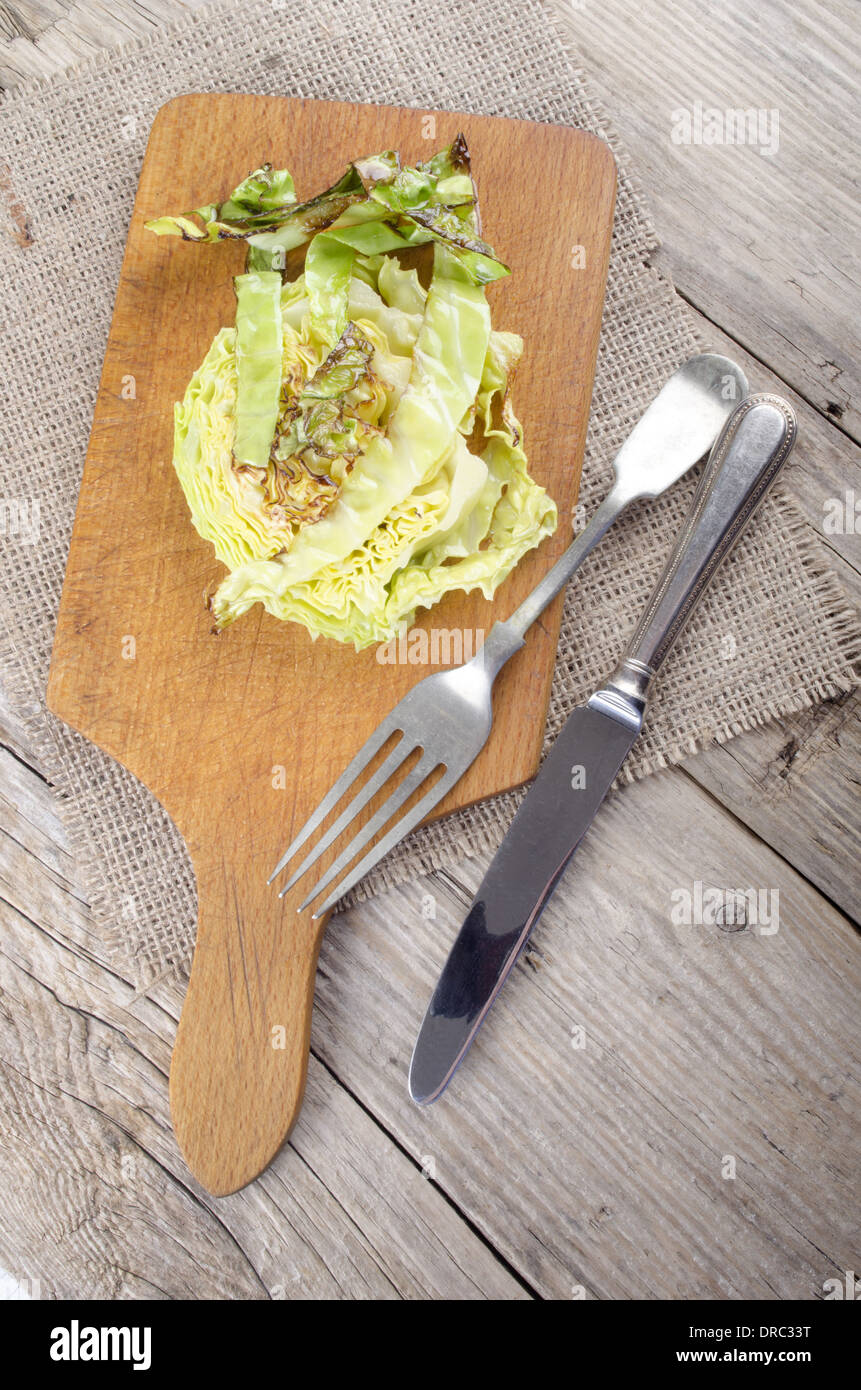 roasted cabbage slice with fork and knife on a wooden board Stock Photo ...
