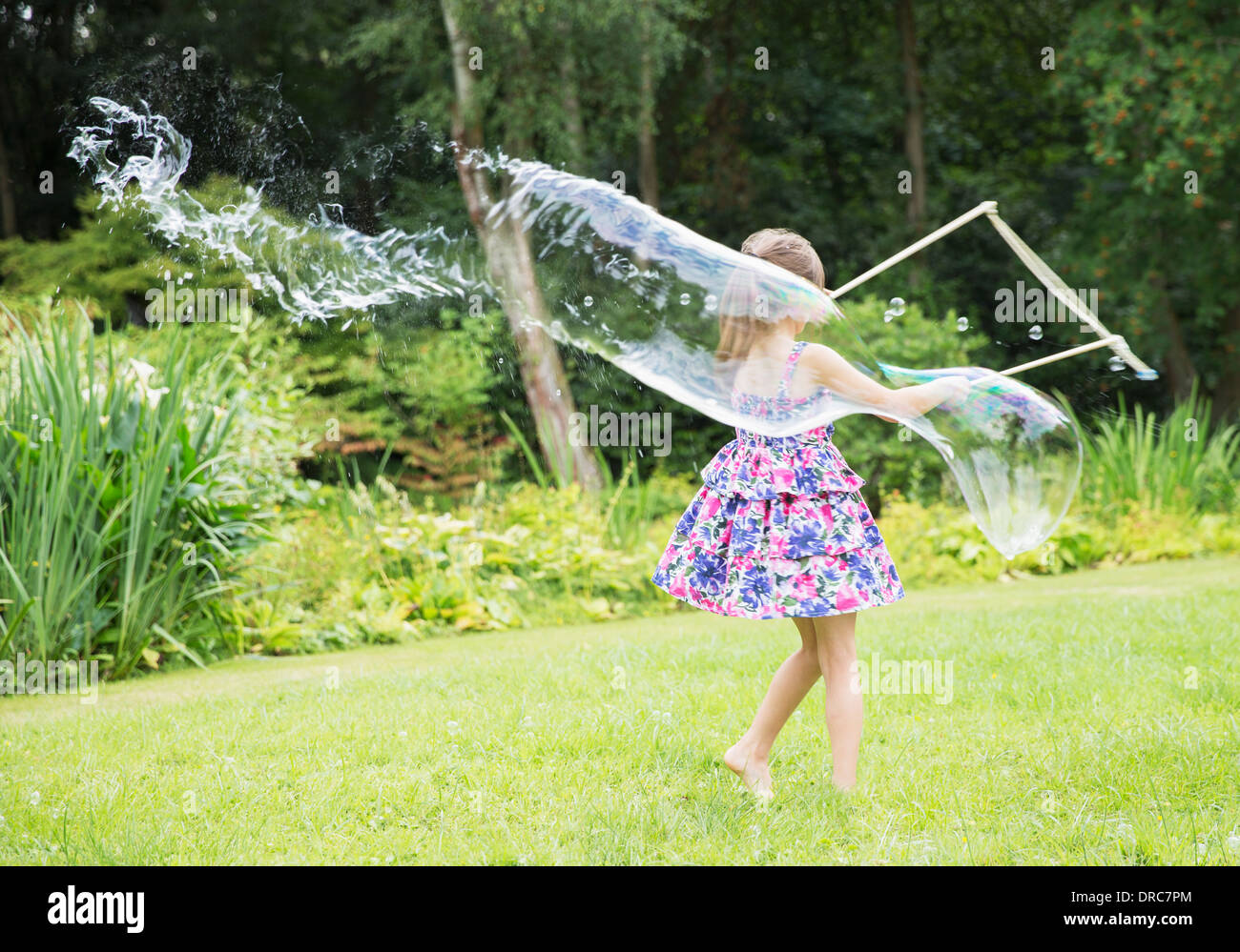 Girl making large bubbles in backyard Stock Photo - Alamy