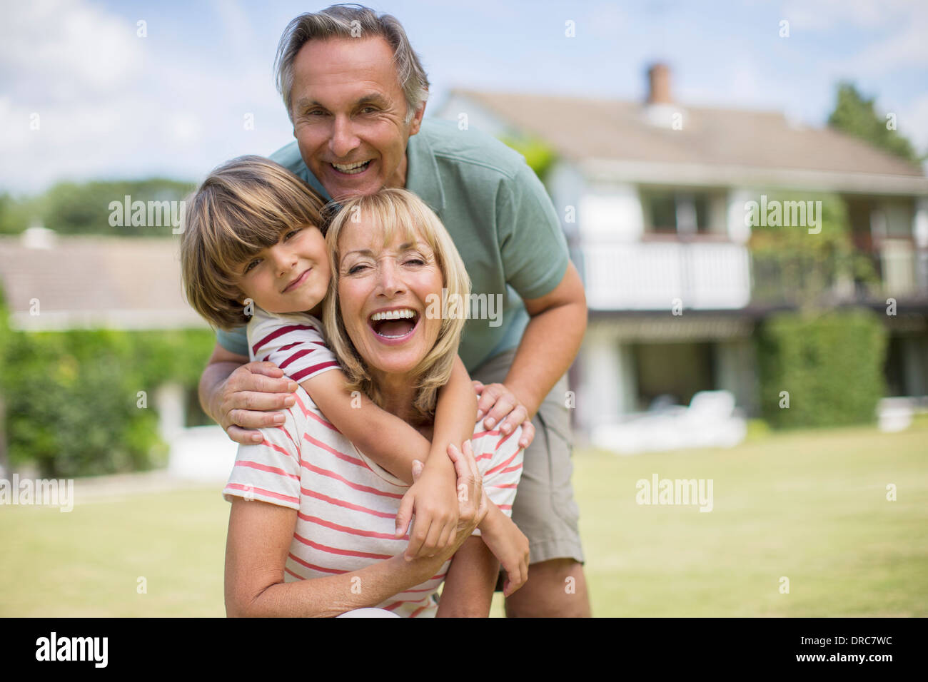 Grandparents and grandson hugging in backyard Stock Photo - Alamy