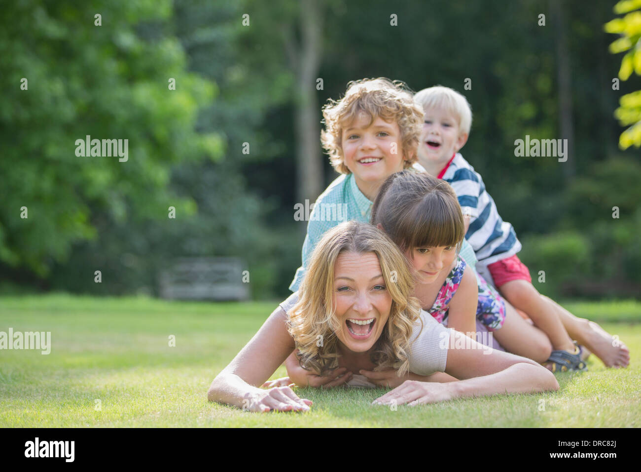 Children laying on mother in grass Stock Photo - Alamy