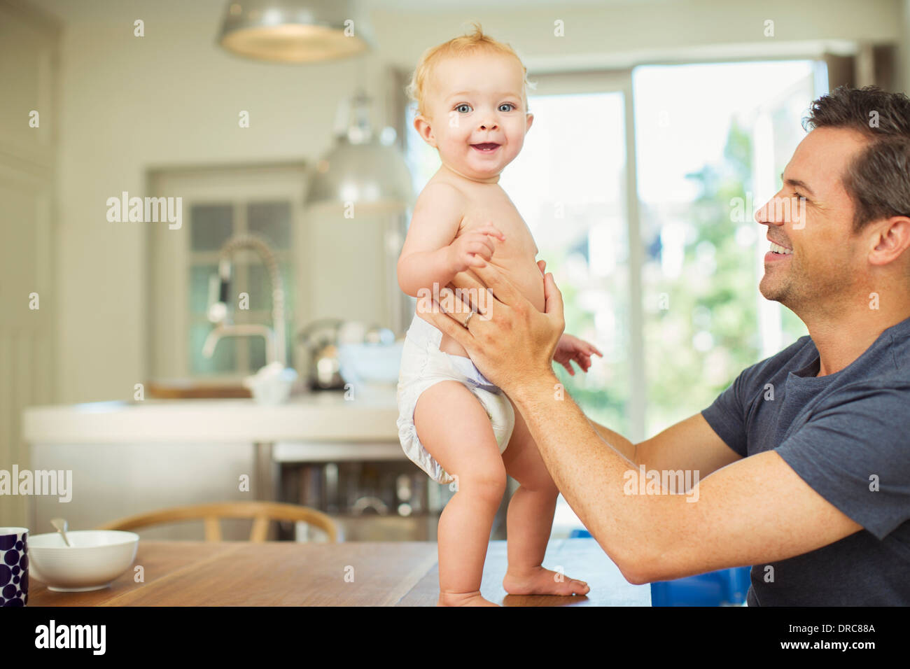 Father helping baby walk on table Stock Photo - Alamy