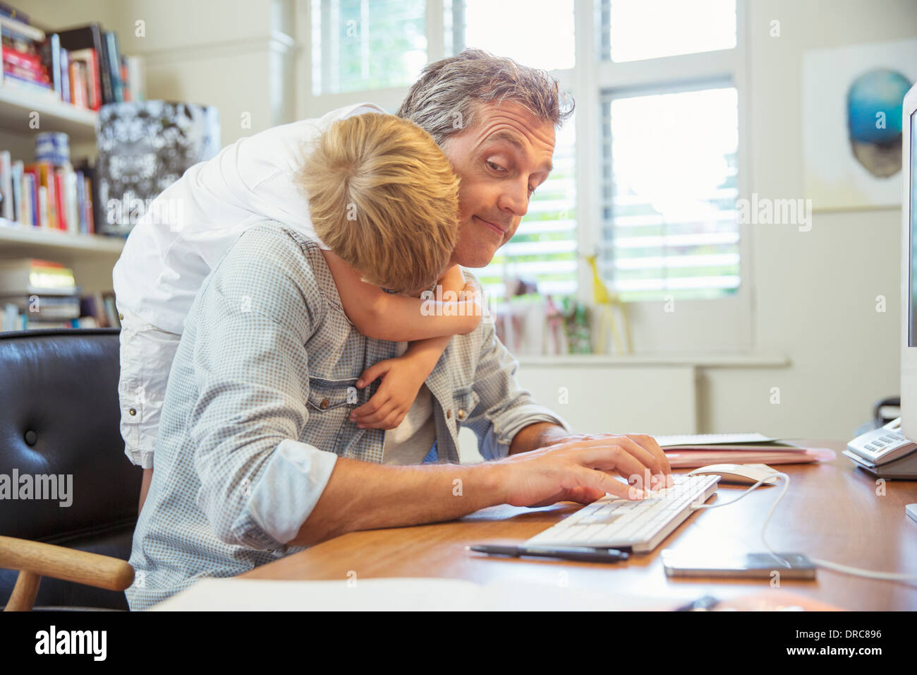 Boy hugging working father Stock Photo - Alamy