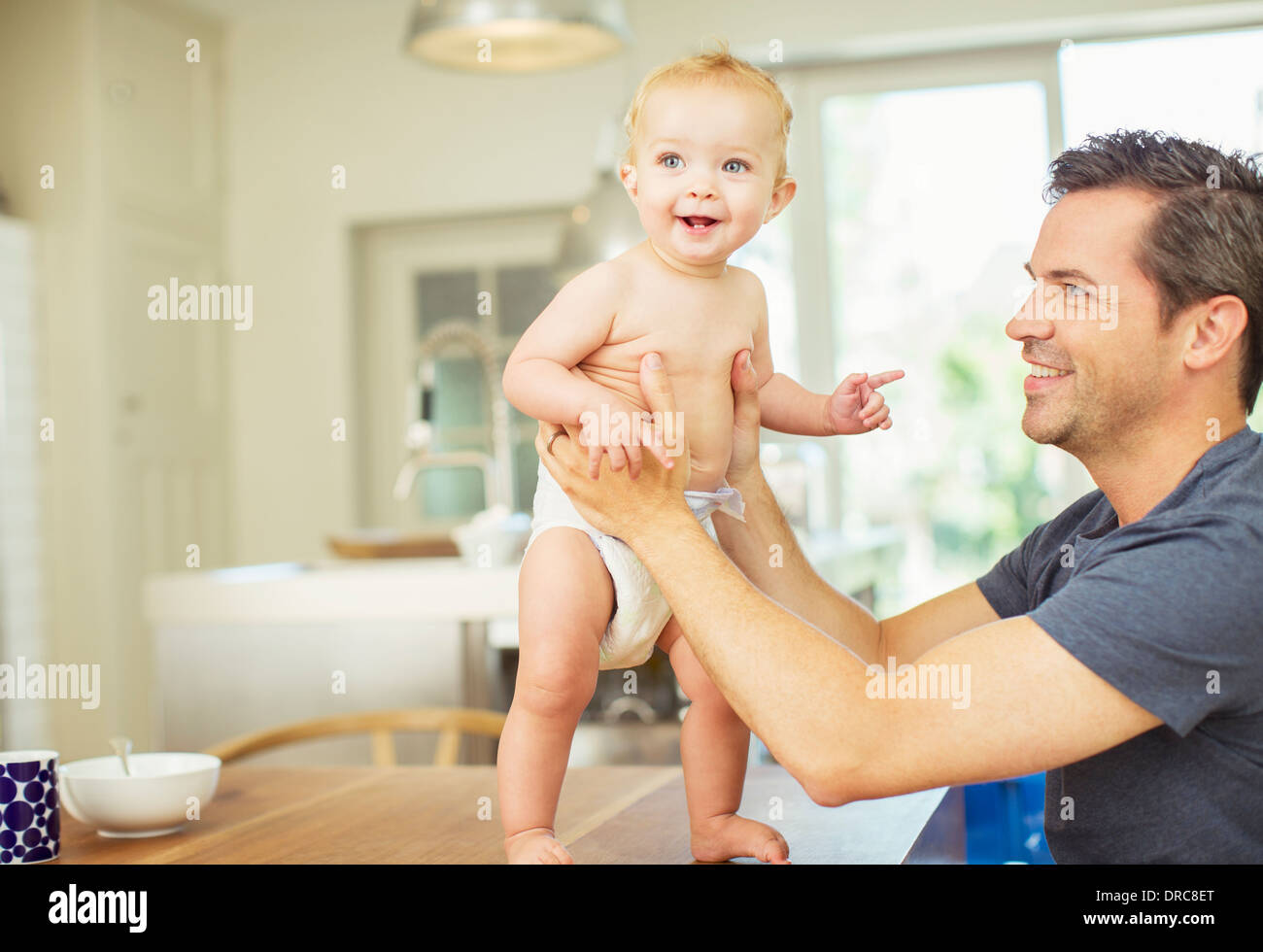 Father helping baby walk on table Stock Photo - Alamy