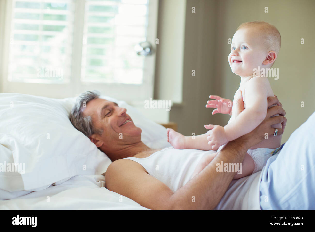 Father playing with baby on bed Stock Photo - Alamy