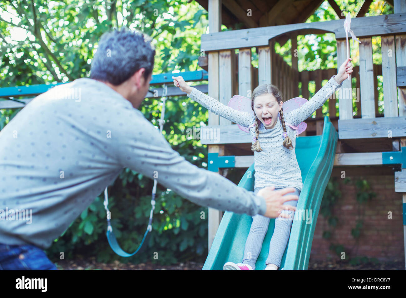 Father catching daughter on slide Stock Photo - Alamy