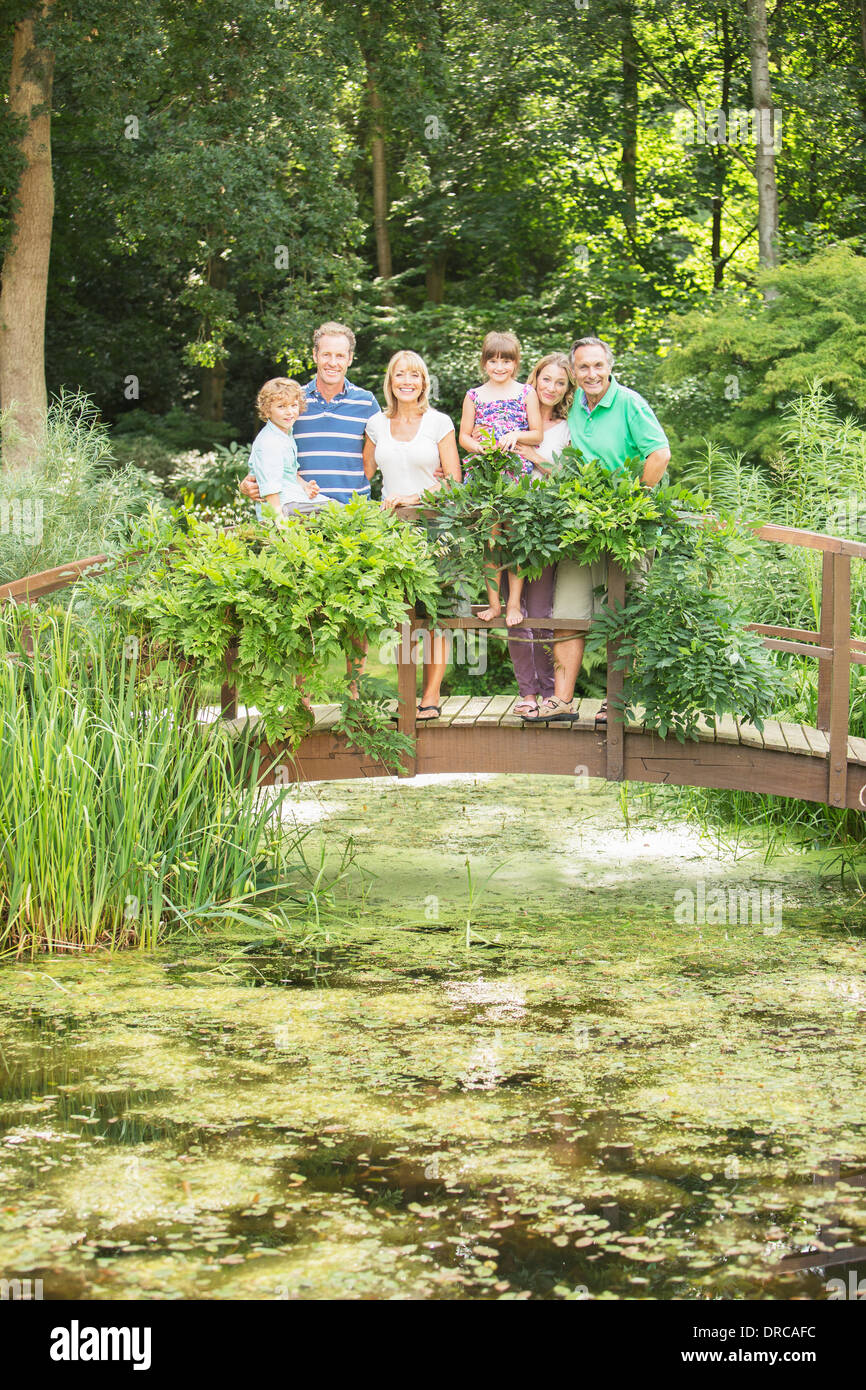Multi-generation family standing on wooden footbridge over pond Stock ...