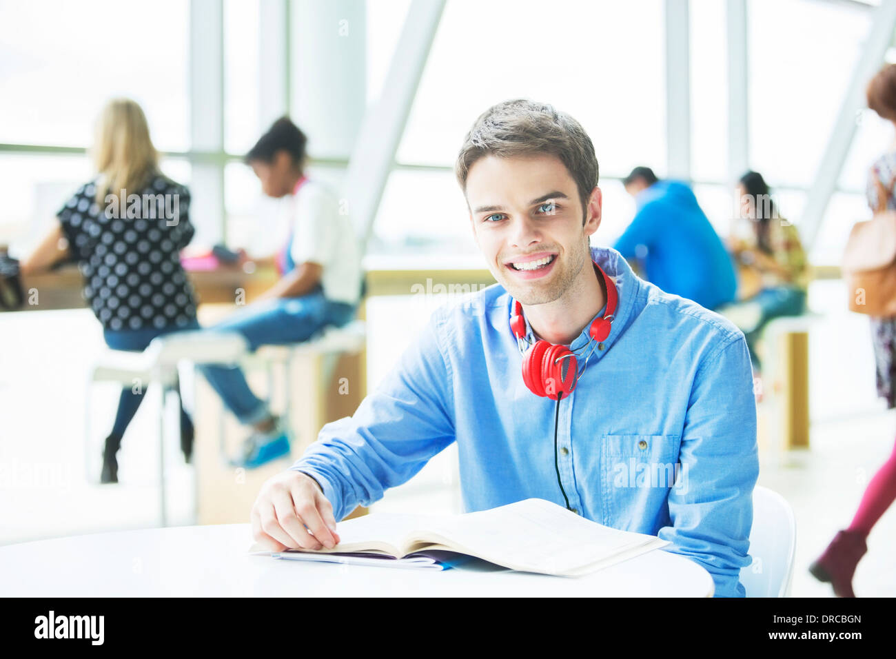 Close up portrait of a smiling male student with stack of books at the ...