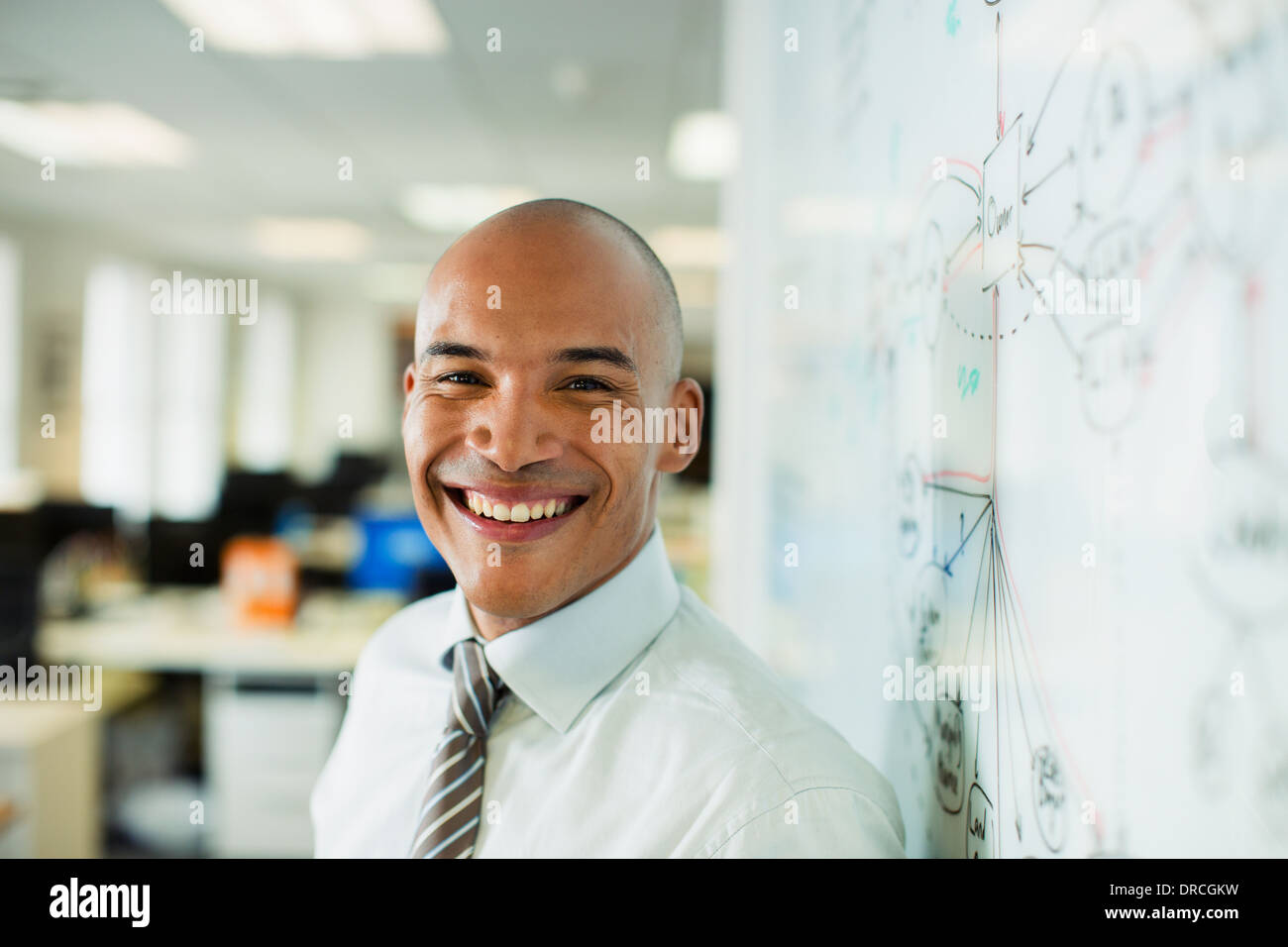Businessman smiling at whiteboard in office Stock Photo - Alamy