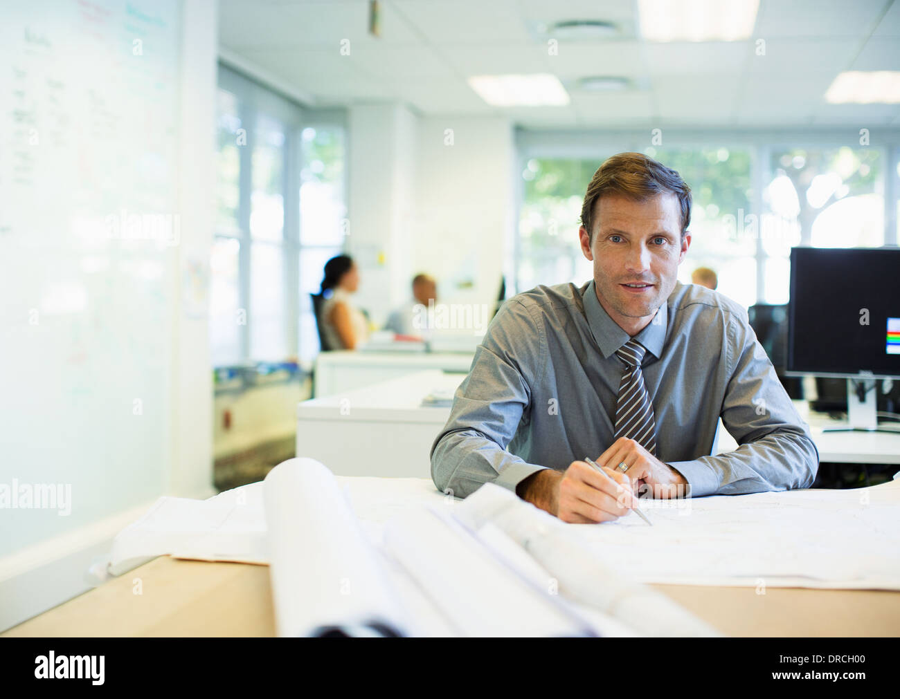 Businessman reading blueprints in office Stock Photo - Alamy