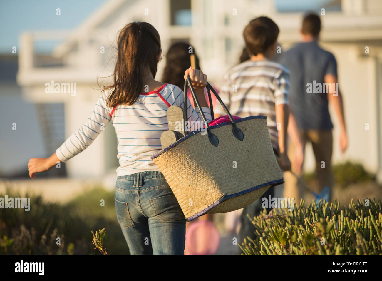 Girl with beach bag following family Stock Photo - Alamy