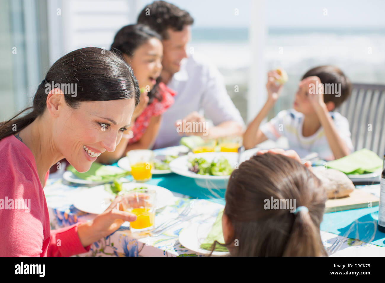 Family eating lunch at table on sunny patio Stock Photo - Alamy