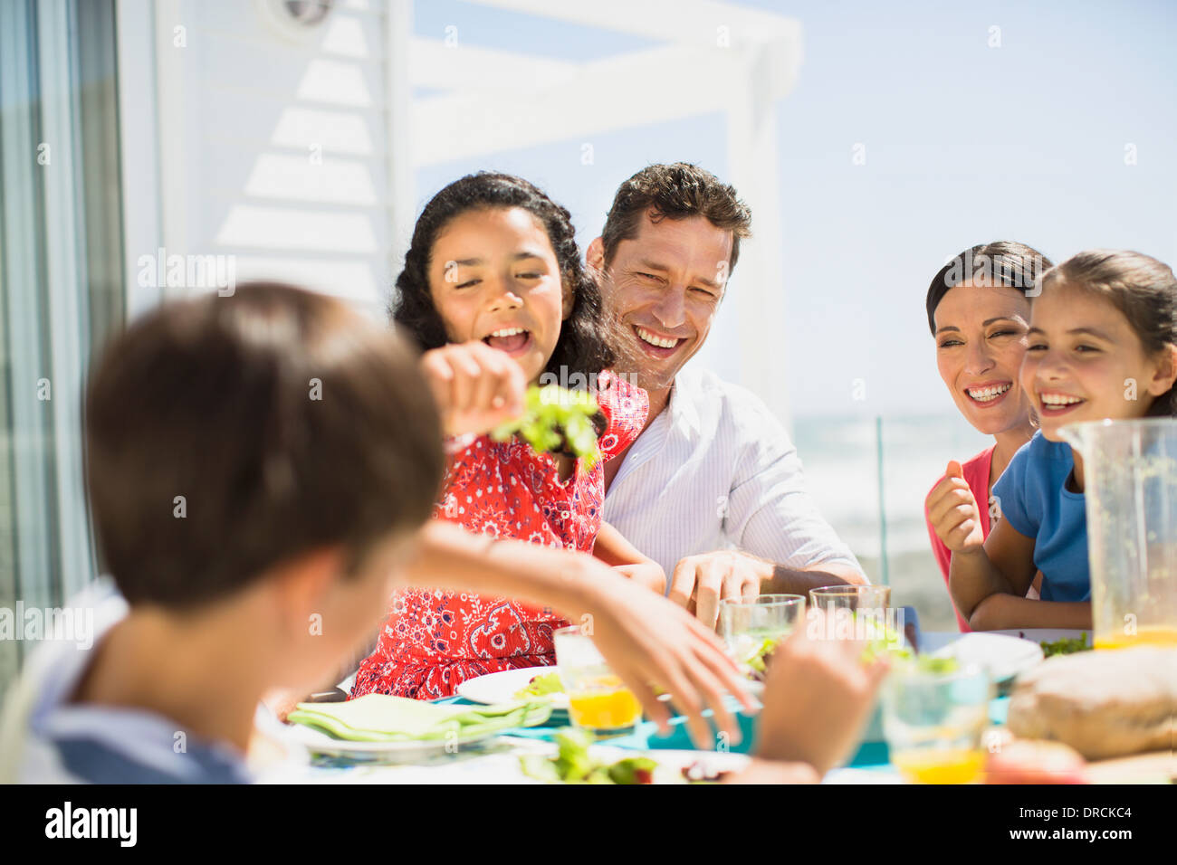 Family eating lunch at table on sunny patio Stock Photo - Alamy