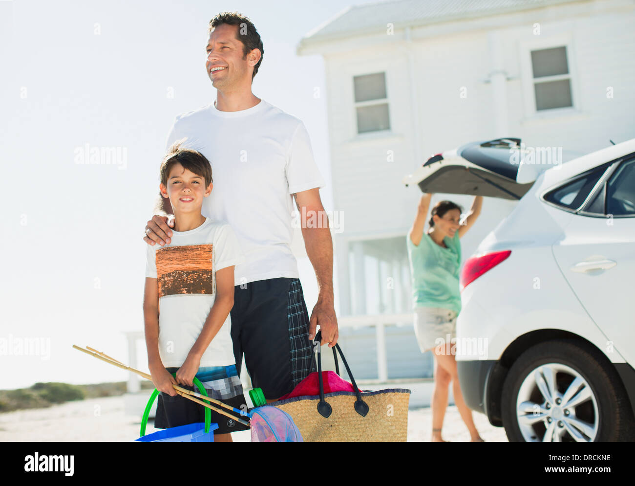 Father and son hugging outside car in sunny driveway Stock Photo - Alamy