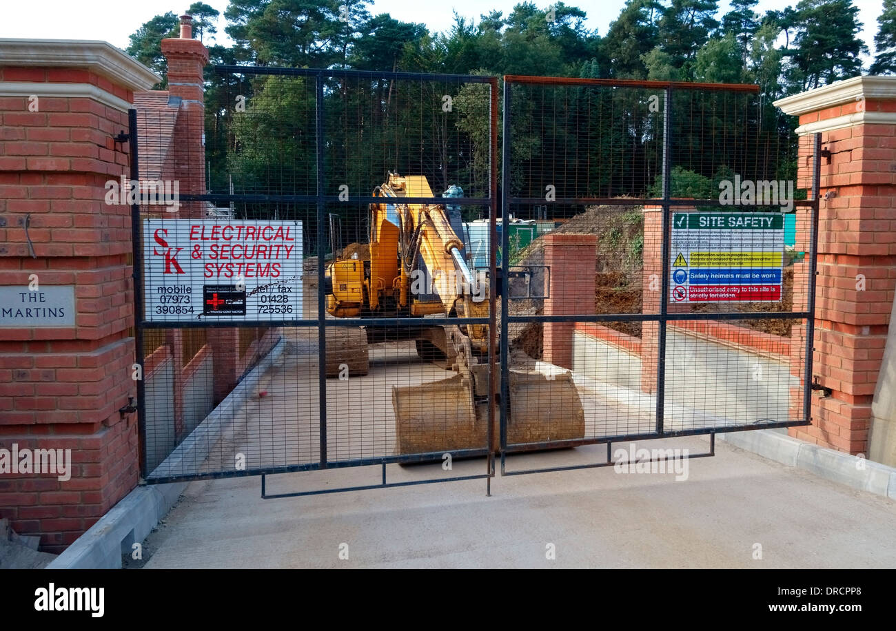 A digger being used to block gates on a building site Stock Photo - Alamy