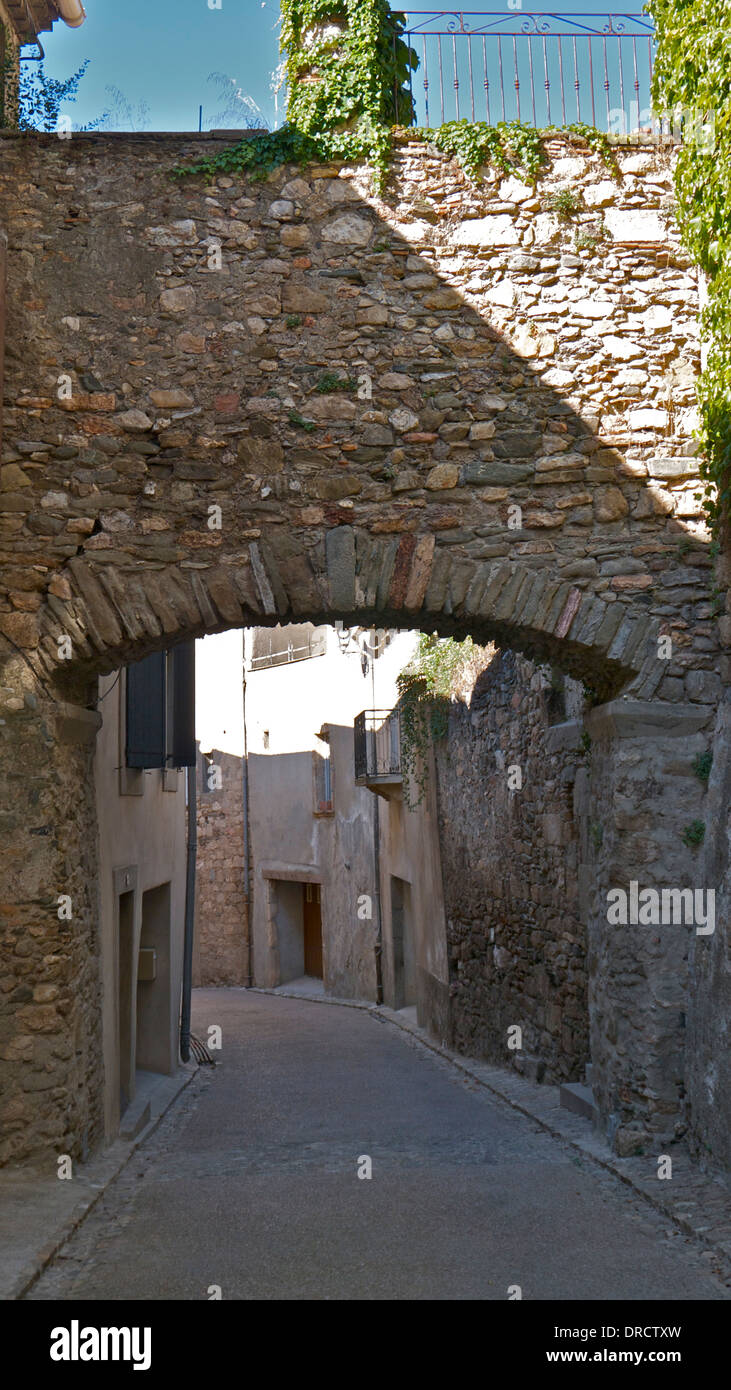 An ancient bridge over a cobbled road in the old historic town Caunes ...