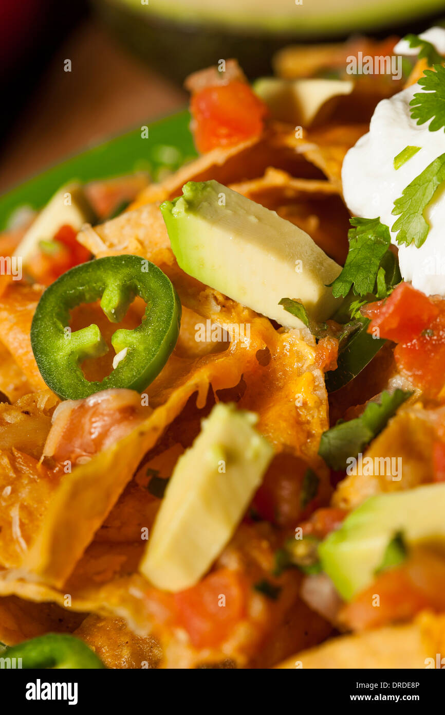 Homemade Unhealthy Nachos with Cheese, Sour Cream, and Vegetables Stock ...