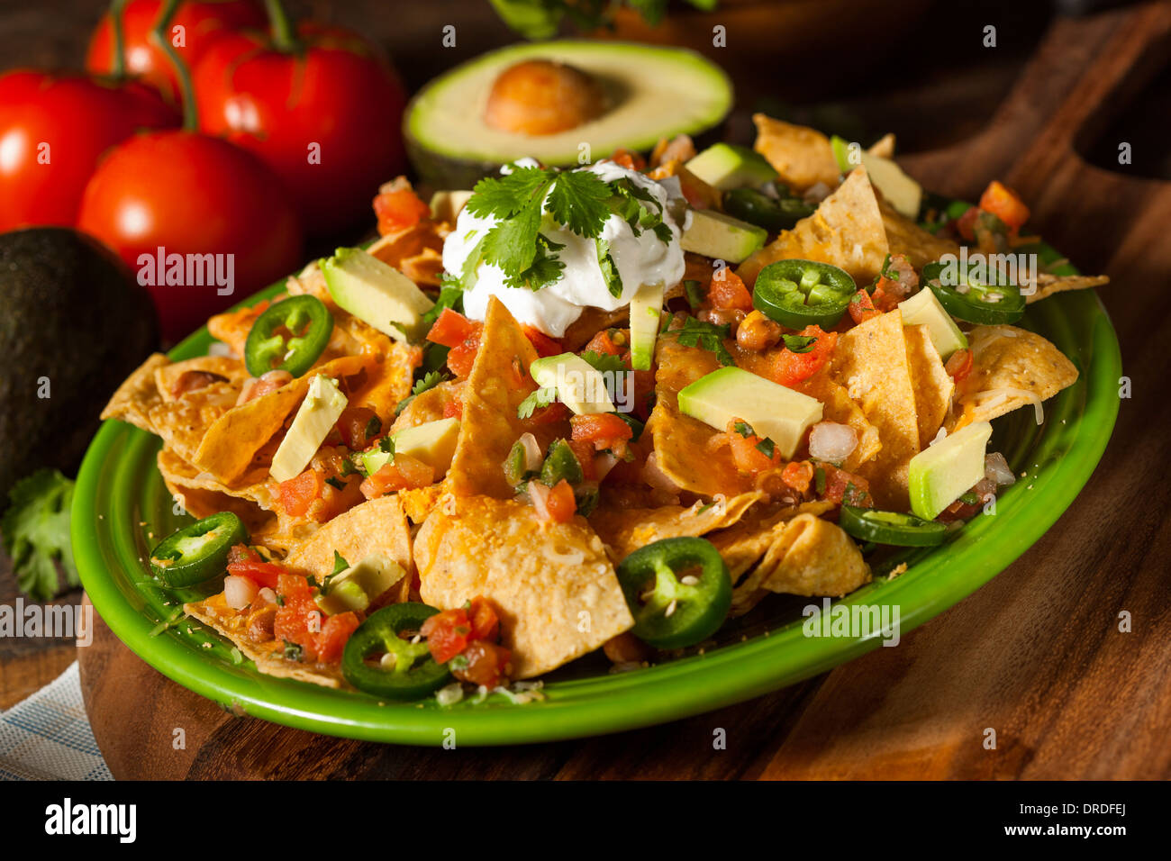 Homemade Unhealthy Nachos with Cheese, Sour Cream, and Vegetables Stock ...