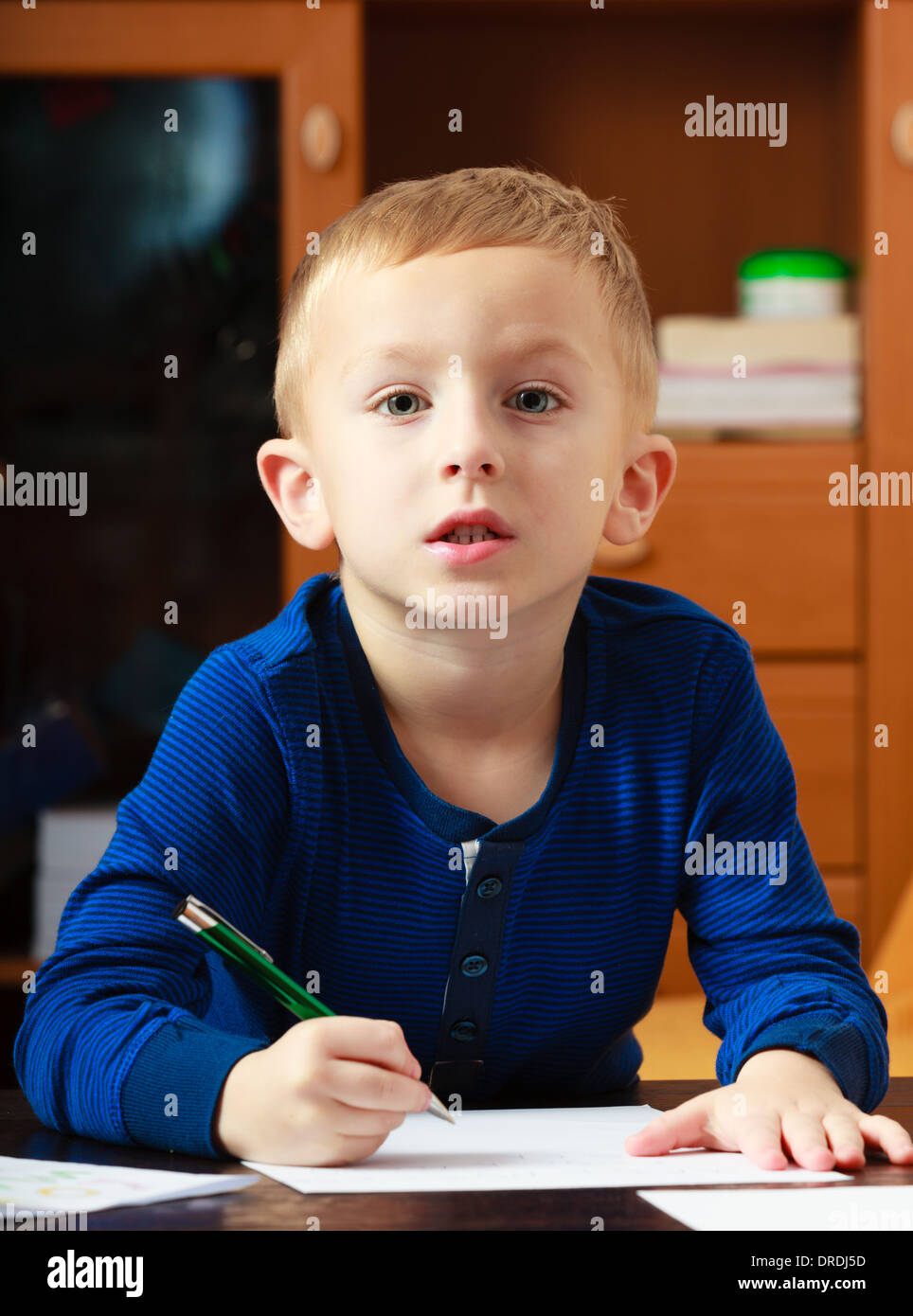 Happy childhood. Blond boy child kid with pen writing on piece of paper ...