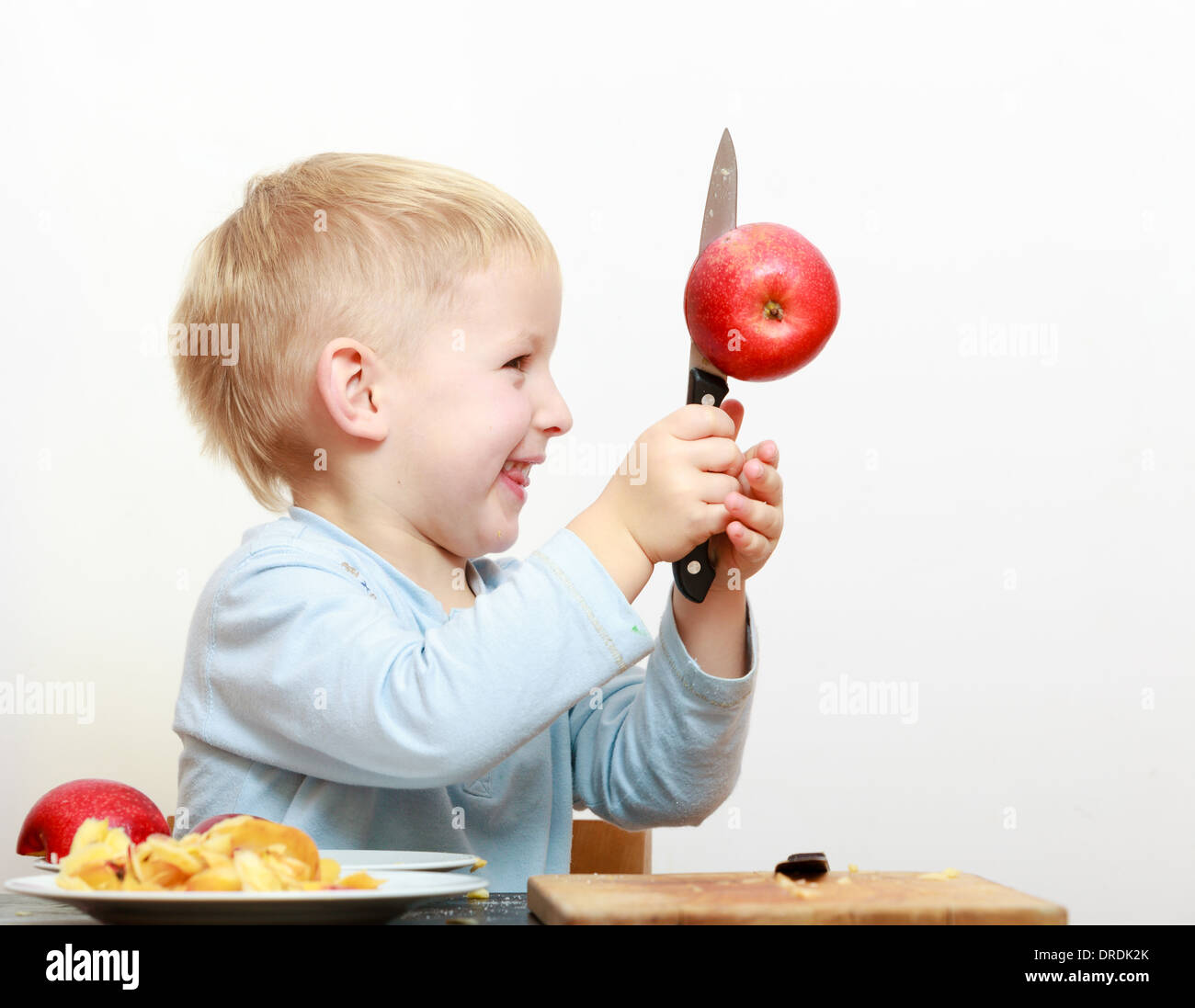 Blond boy child kid preschooler with kitchen knife cutting fruit apple ...
