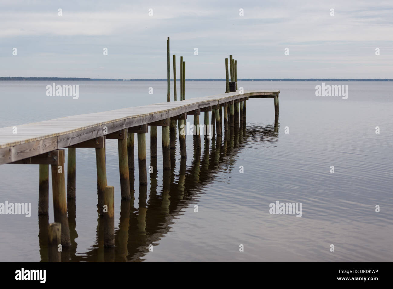 Pier with reflection in the water under cloudy sky Stock Photo - Alamy