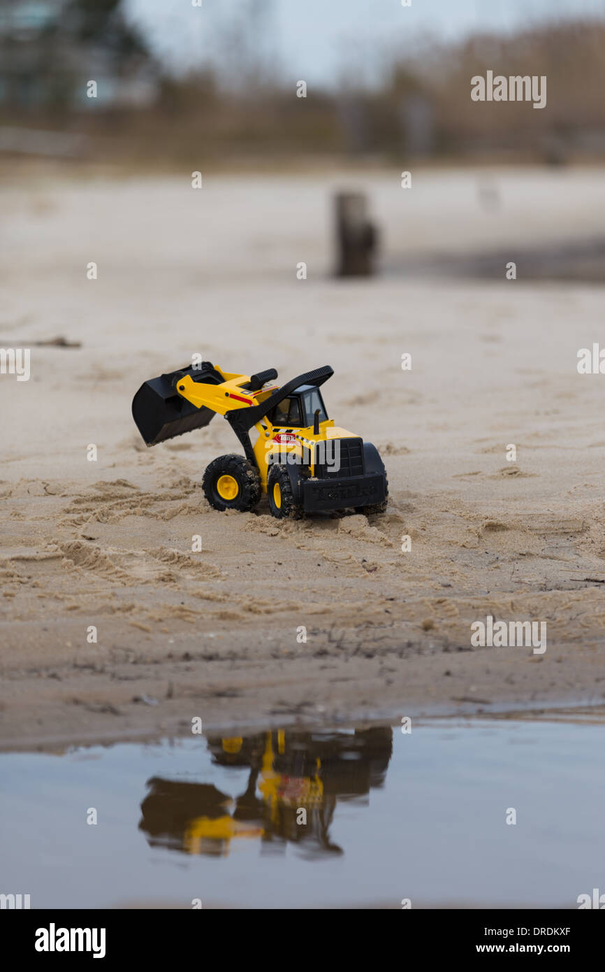 Tonka toy backhoe on a sandy beach, reflecting on the water Stock Photo ...