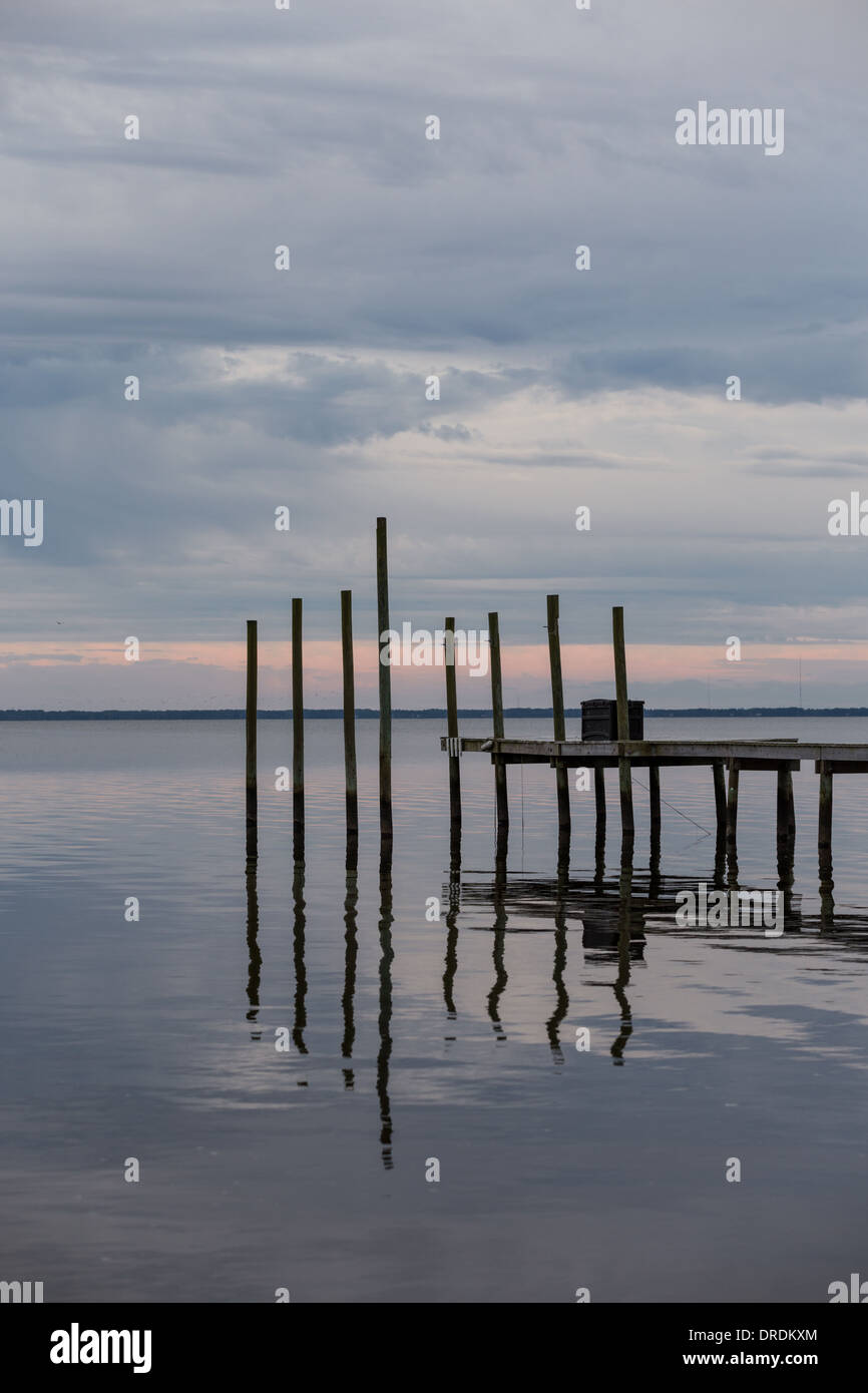 Pier with reflection in the water under cloudy sky Stock Photo - Alamy