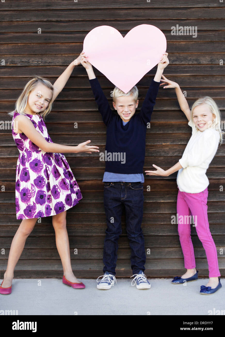 Siblings holding up large paper heart Stock Photo - Alamy