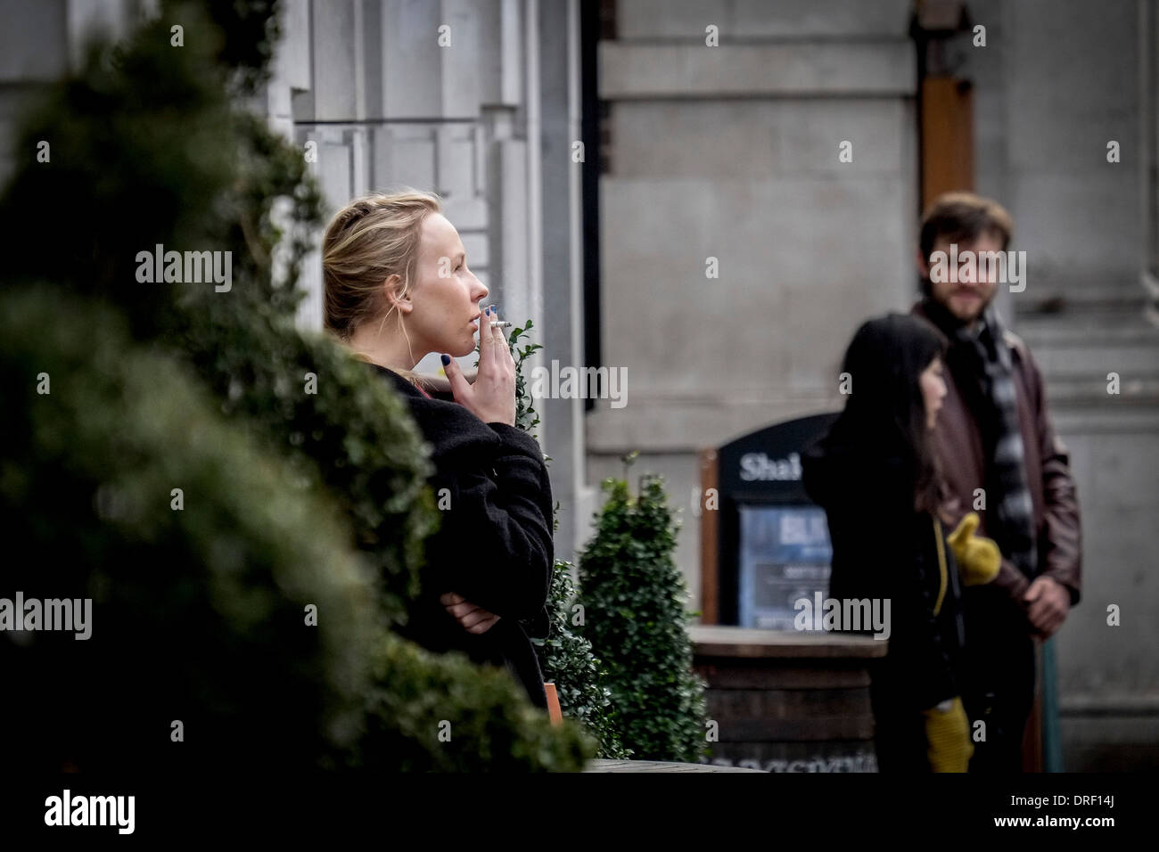 A woman smoking a cigarette outside a building Stock Photo - Alamy