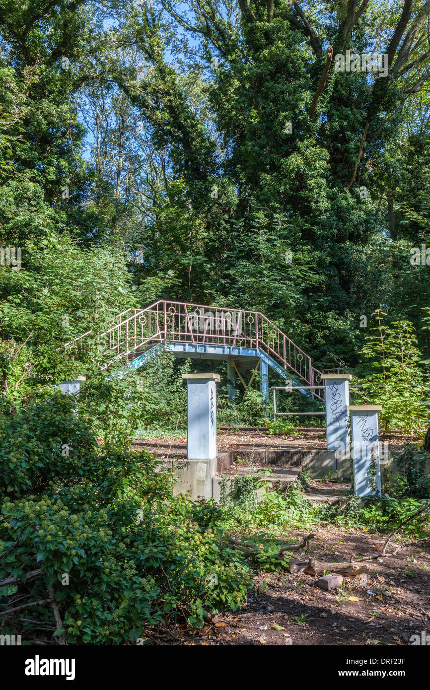 Paths and bridge overgrown with plants and weeds at derelict, disused ...