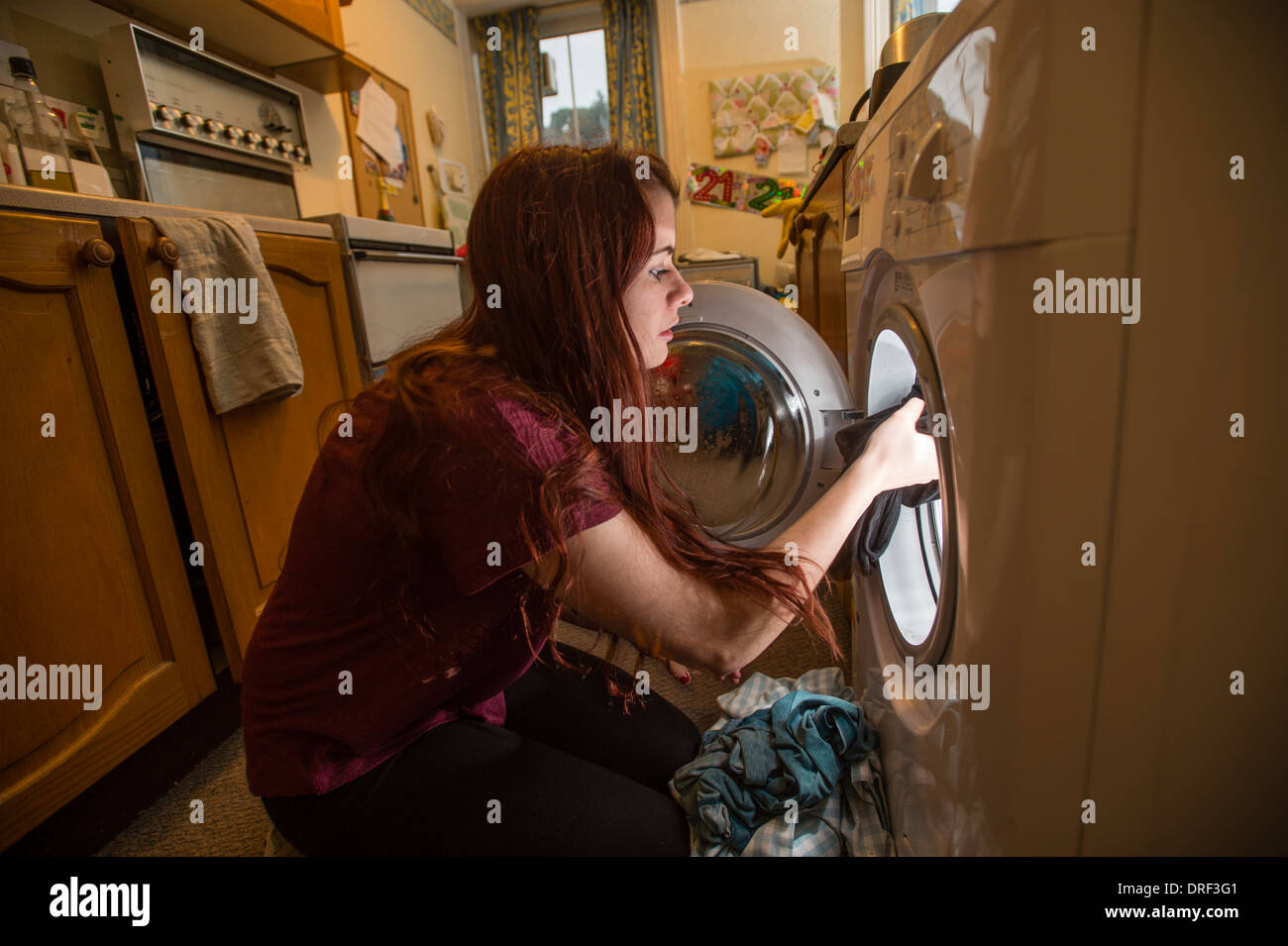 A young single woman university student doing the laundry washing her ...