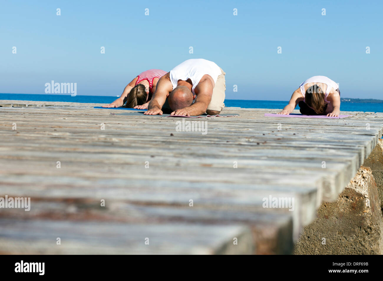 People practising yoga on boardwalk, rabbit pose Stock Photo - Alamy