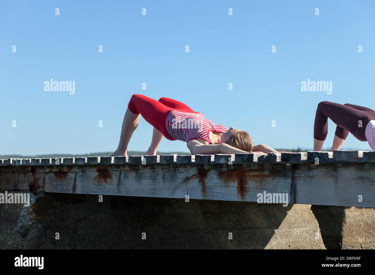 People practising yoga on boardwalk doing bridge pose Stock Photo - Alamy