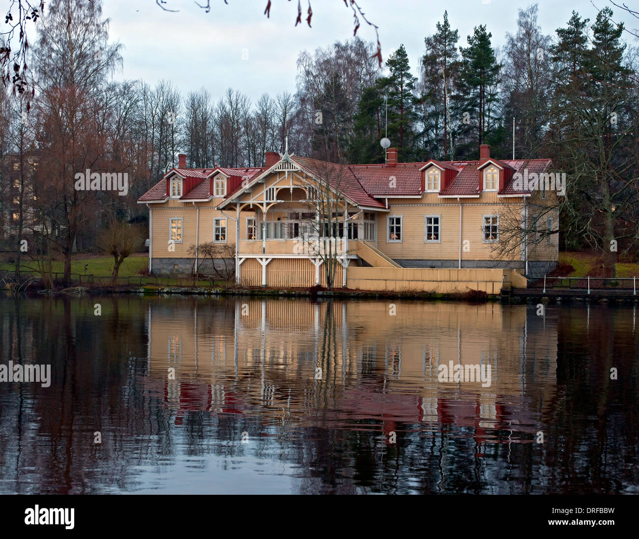 Beige house with a roof of red tiles on the lake, in the evening, near ...