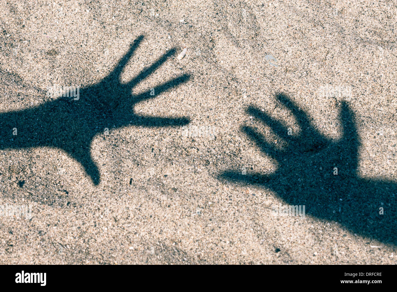 Shadow of two hands over sand background Stock Photo - Alamy