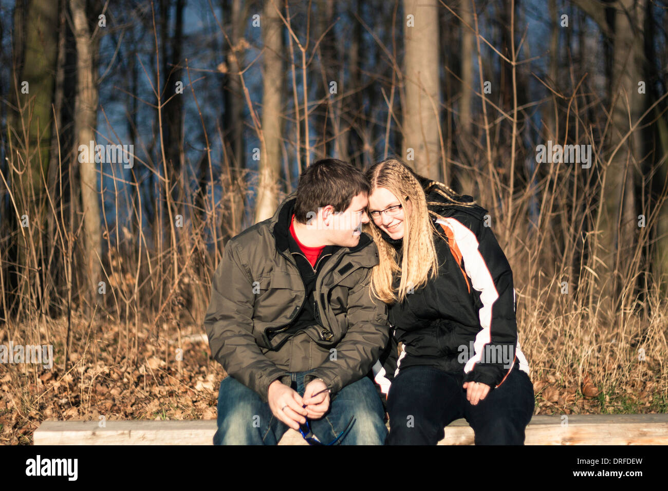 Two young happy people sitting on park bench Stock Photo - Alamy