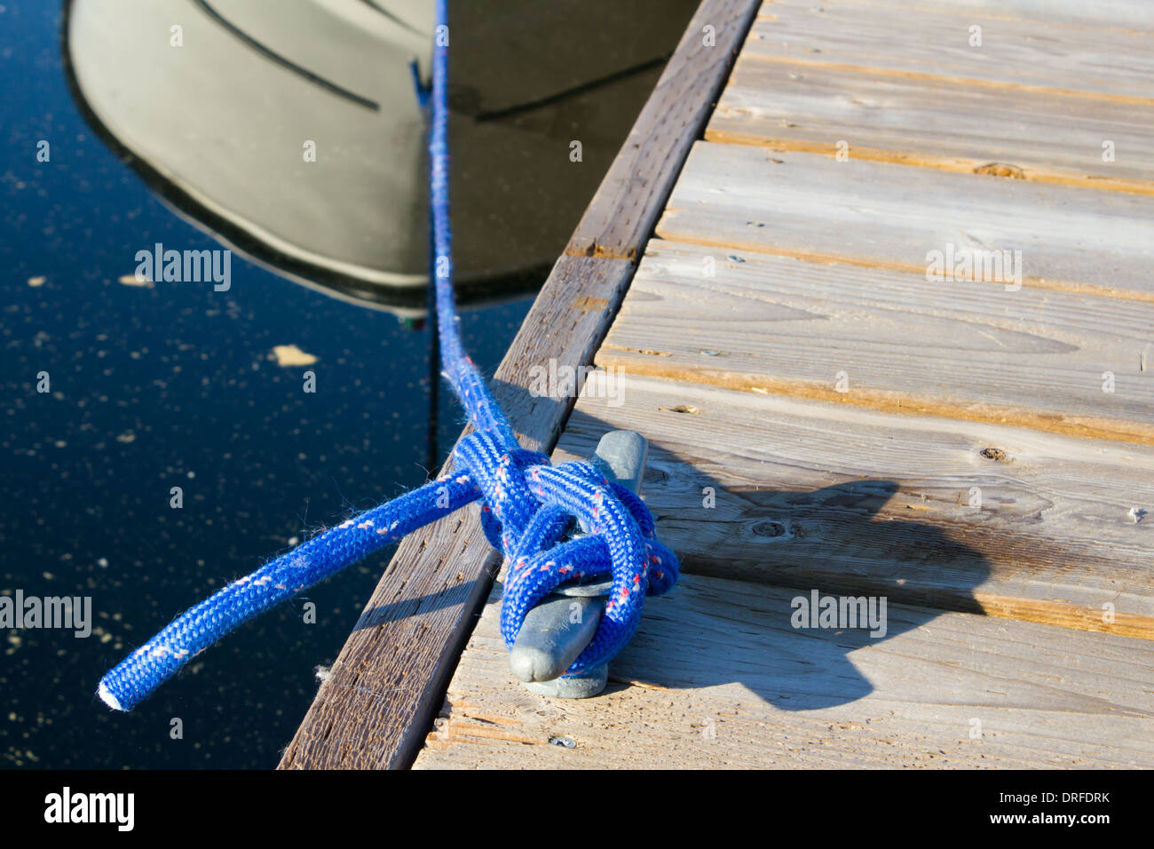 Boat tied up on a wooden dock with blue rope Stock Photo - Alamy