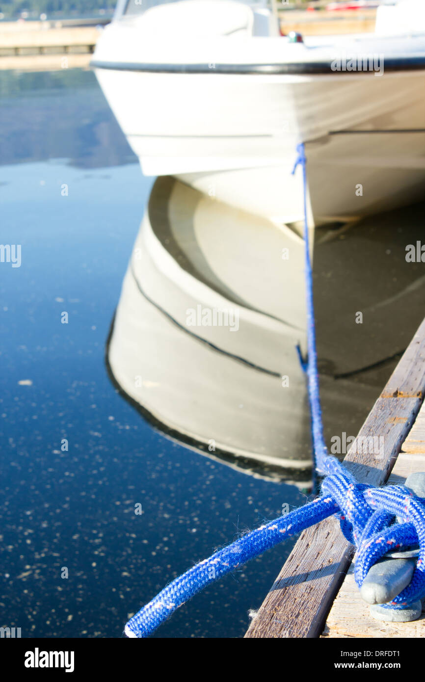 Boat tied up on a wooden dock with blue rope Stock Photo - Alamy