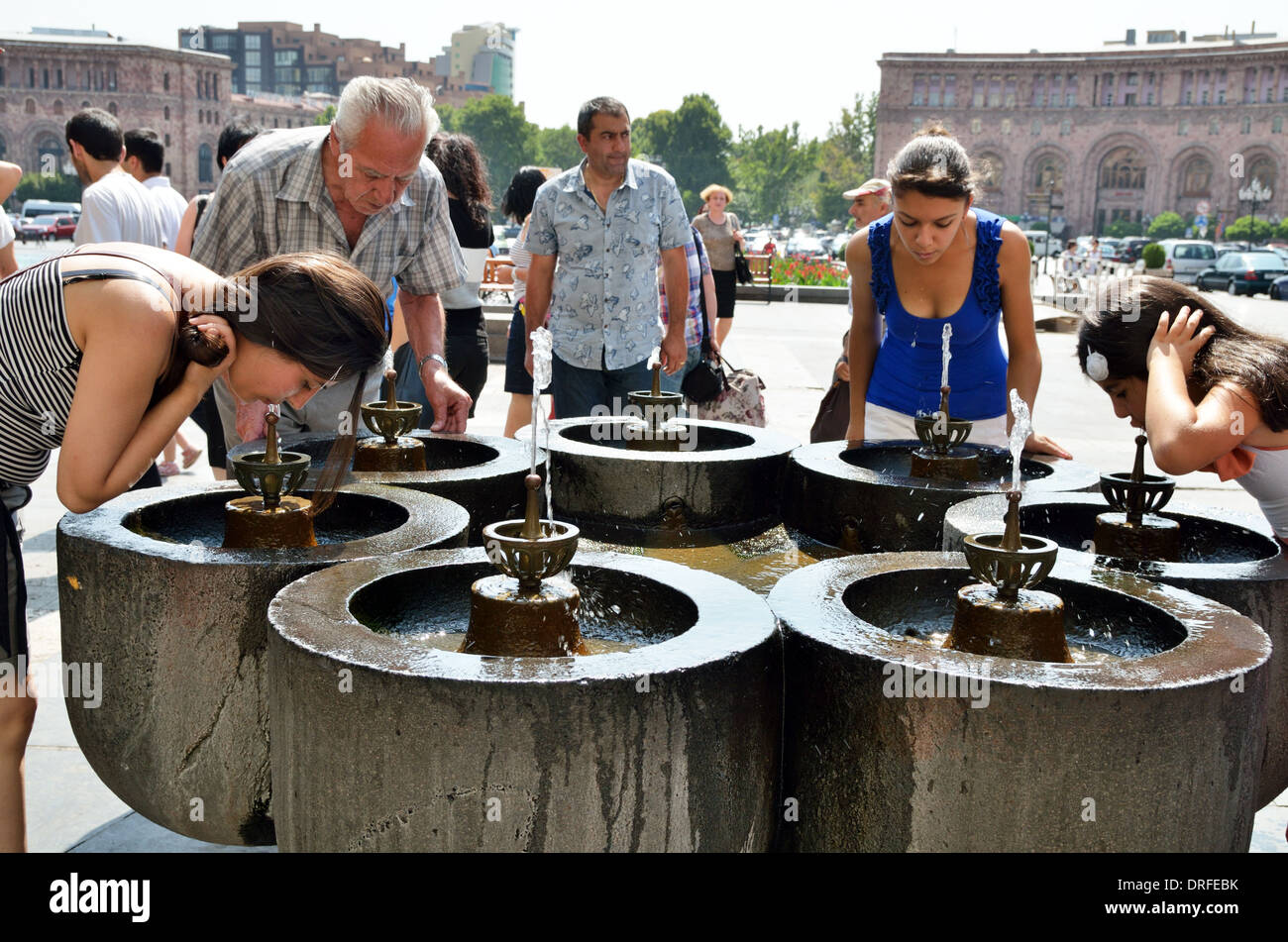 A group of people take a drink from Yerevan's natural drinking water ...