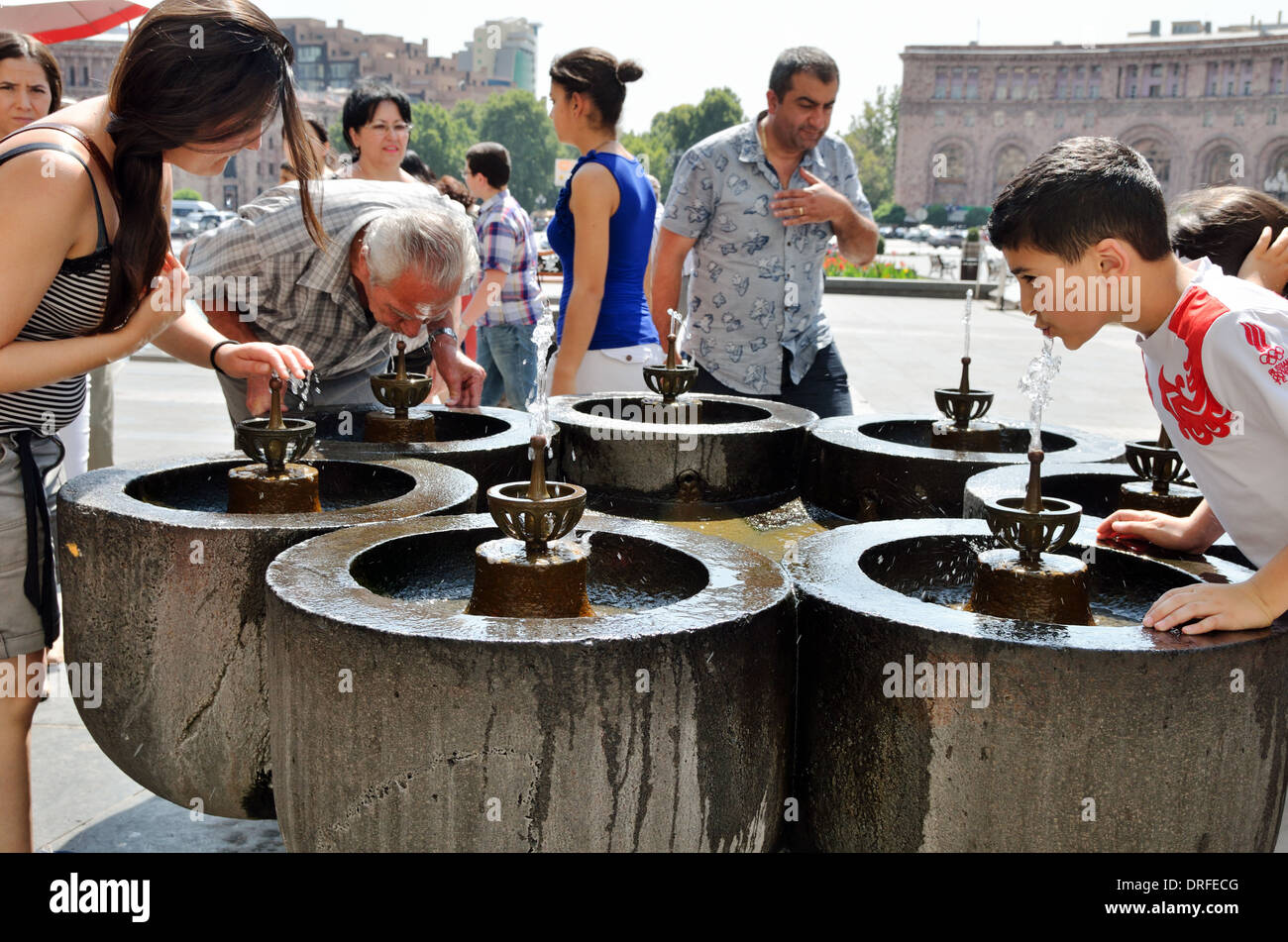 A group of people take a drink from Yerevan's natural drinking water ...