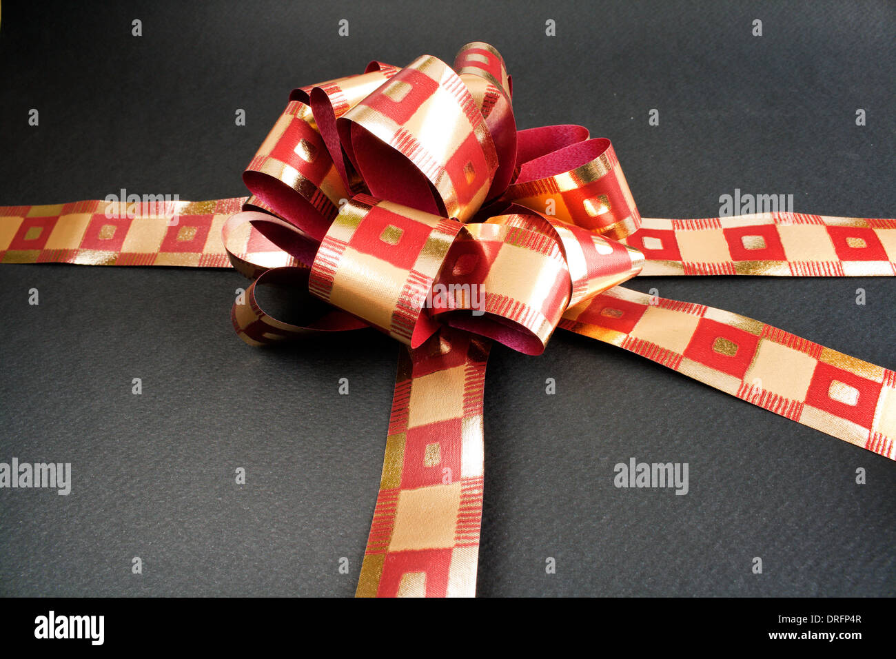 A red ribon tied in a bow over a black background Stock Photo - Alamy