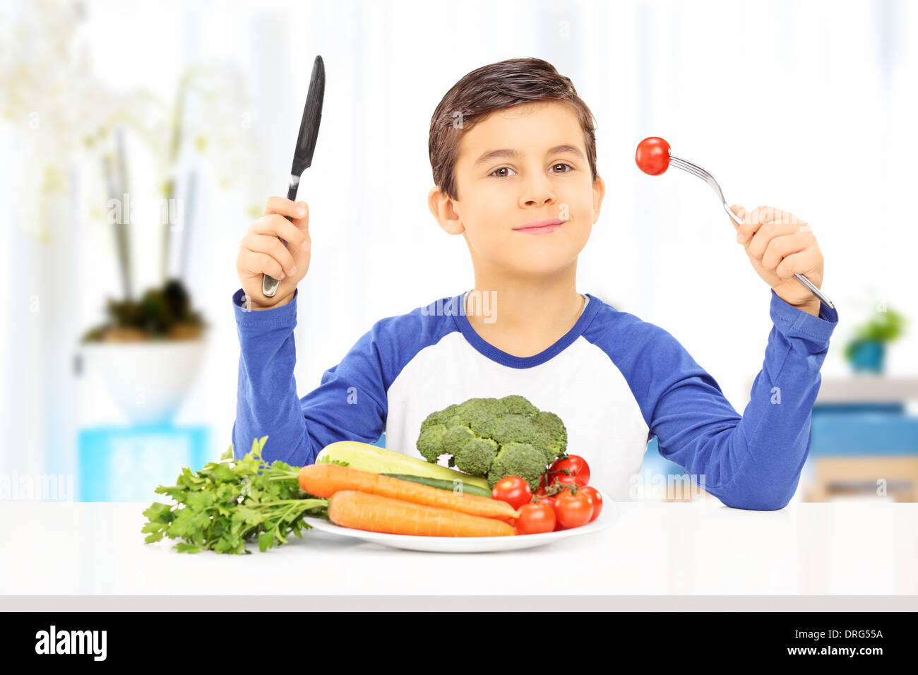 Young boy eating healthy meal seated at a table Stock Photo - Alamy