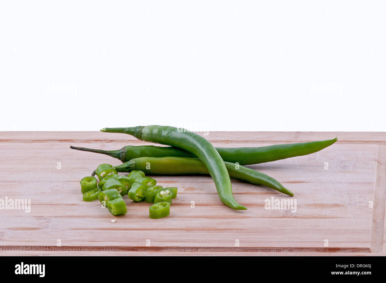 chopped green chillies with pile of green chillies on aged chopping ...