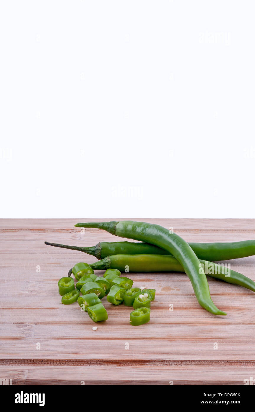 chopped green chillies with pile of green chillies on aged chopping ...