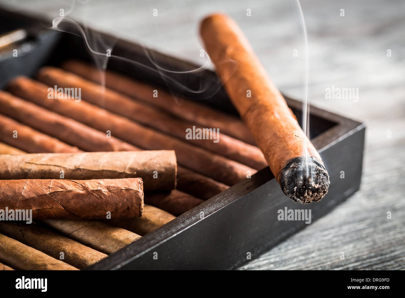 Burning cigar with smoke on old humidor Stock Photo - Alamy