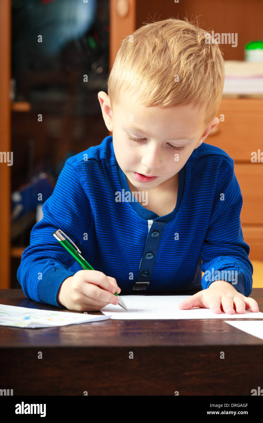 Happy childhood. Blond boy child kid with pen writing on piece of paper ...