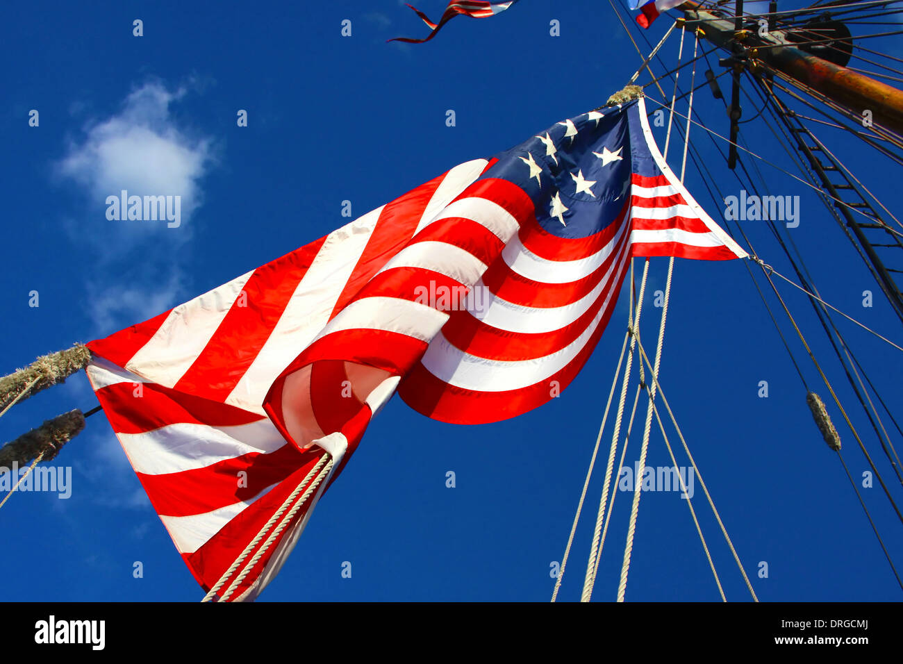 United States flag blows in the wind on the mast of a tall sailing ship ...