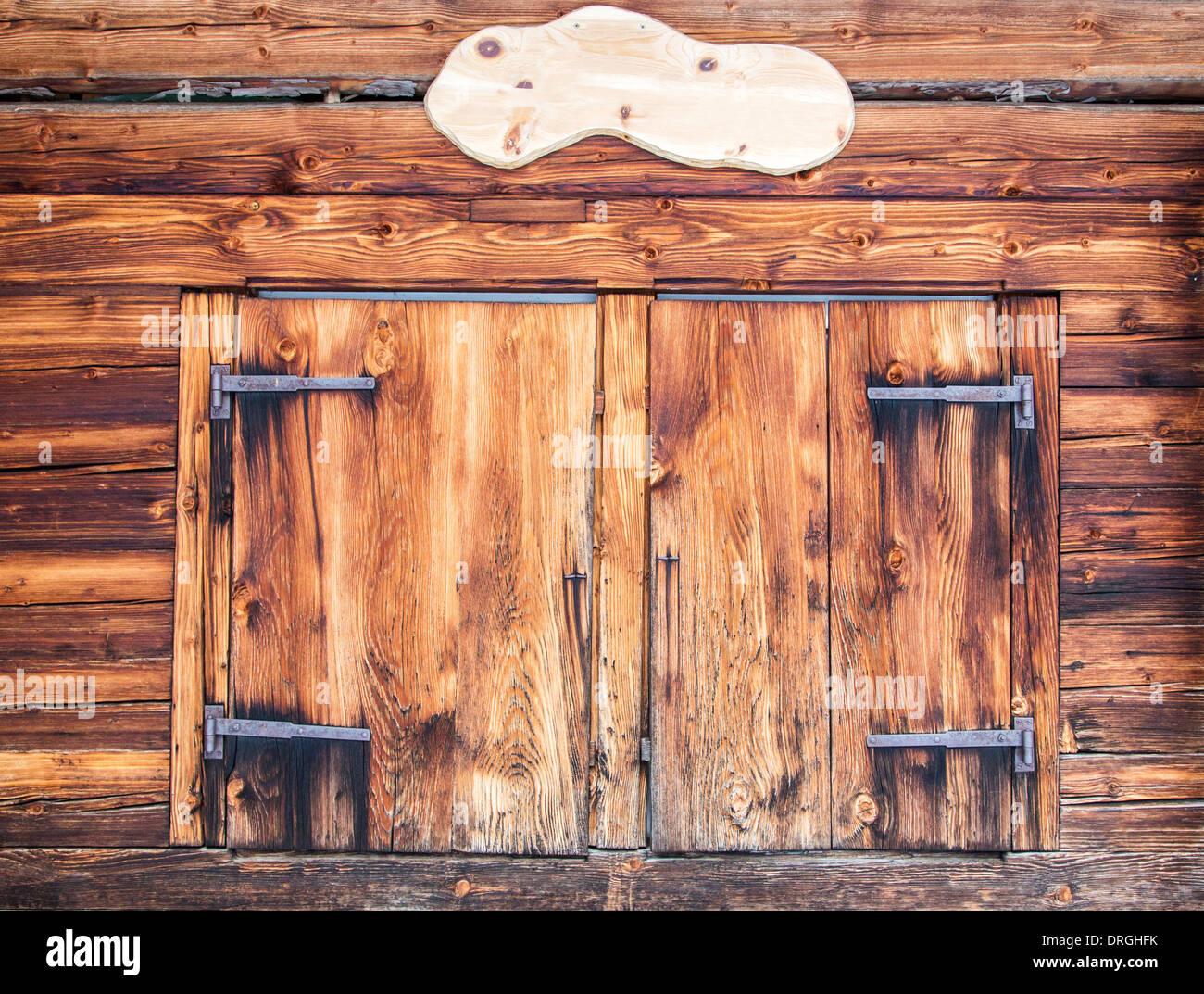 Wooden facade of a mountain hut with closed window shutters and empty ...